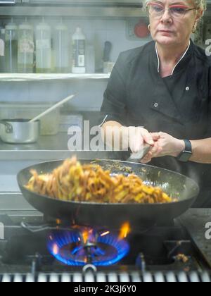 mixing pasta with sauce in a big professional used professional pan ...