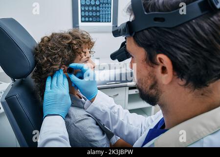 Ear check-up in child, otolaryngology. Curly boy patient during ear ...