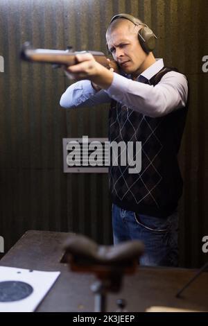 Man aims at a target with a semi-automatic rifle in shooting range ...