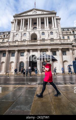 A pedestrian with an umbrella walks past the Bank of England. UK braces ...
