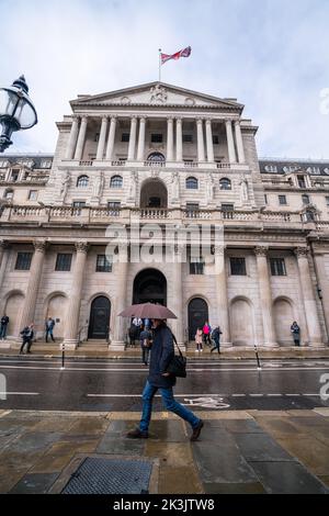 A pedestrian with an umbrella walks past the Bank of England. UK braces ...