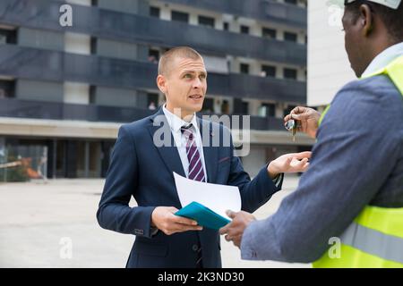 African-american contractor hands the keys to a man customer Stock ...