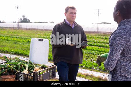 Two farmers talking among themselves during a break in work on field ...