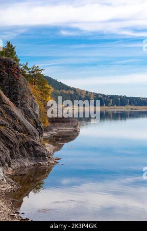 Beautiful, wide autumn river among forests and rocky shore. A calm and ...