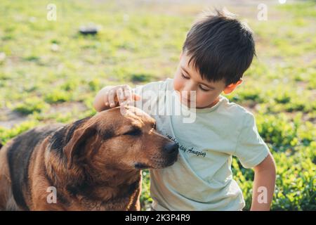 Kid caress dog. Child boy with dog walking outdoor. Kid playing with ...