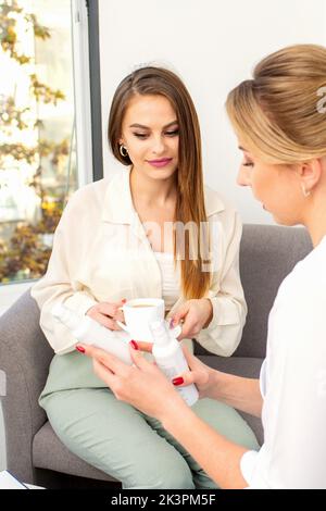 Beautician offering product for the young woman holding white plastic ...