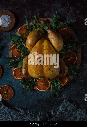 Whole backed chicken on wood plate decorated by dried sliced oranges ...