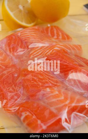A piece of raw fish is vacuum-sealed in a clear plastic bag with a ...