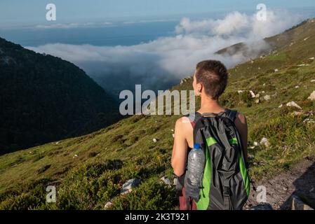 Back view of inspired tourist with heavy backpack watching at mountains ...