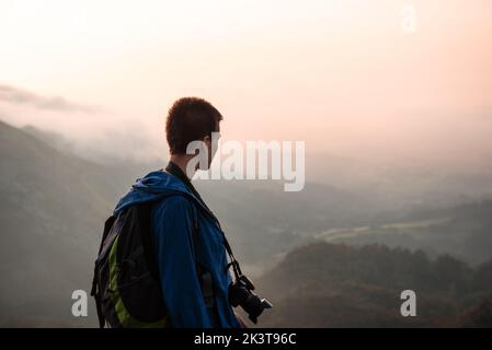 Side view of inspired tourist with heavy backpack watching at mountains ...