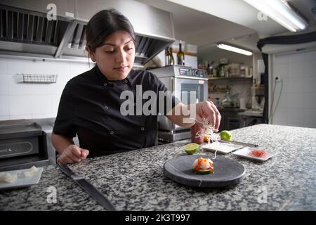 Hispanic female chef putting white daikon on lime slice placed on ...