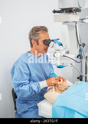 Animal surgeon using operating microscope while injecting medicine into ...