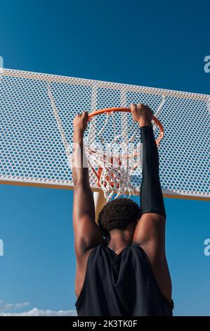 Back view of powerful energetic African American sportsman hanging on ...