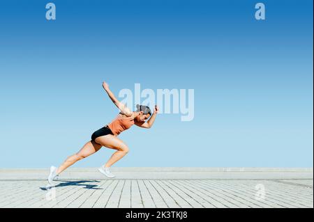 Phases of side view female athlete starting race and running fast on ...