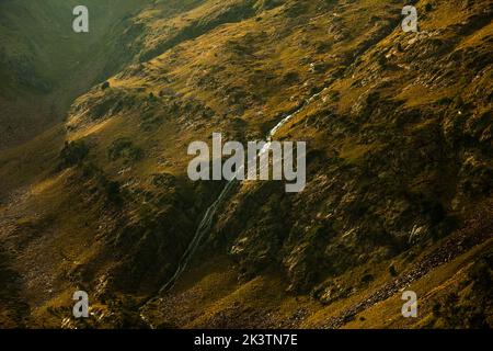 From above of narrow curvy stream running through rough rocky mountain ...