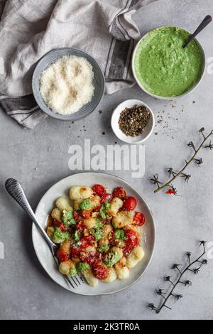 Top view of appetizing gnocchi with pesto sauce served on white plate ...