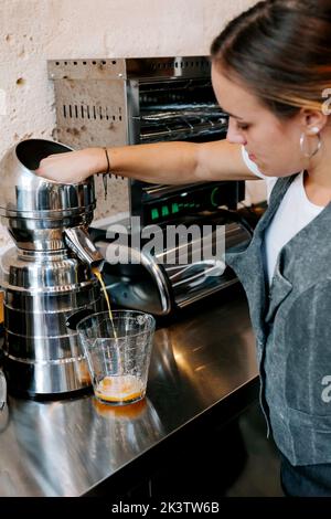 diligent barista preparing citrus fresh juice in shiny juicer at table ...