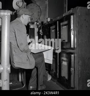 1950s historical, a male operator sitting at a machine sending a telex ...