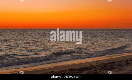 Vibrant orange red sky reflecting in calm ocean after sunset. Minimal ...