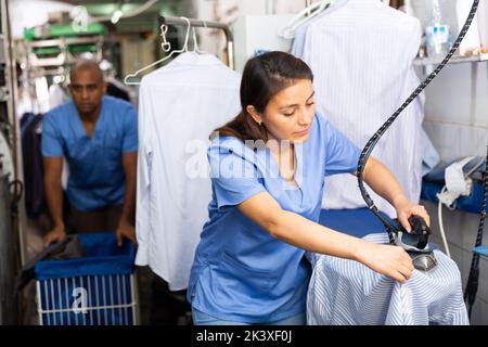 Female laundry worker checking the quality of wash Stock Photo - Alamy
