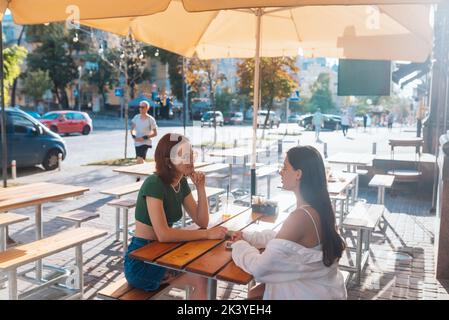 Two pretty girlfriends talking while sitting in a bar outdoors Stock ...