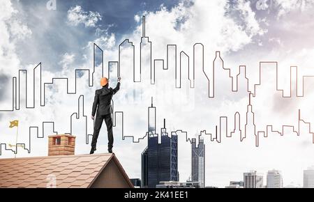 Man architect draw silhouette of modern city on blue sky. Mixed Stock ...