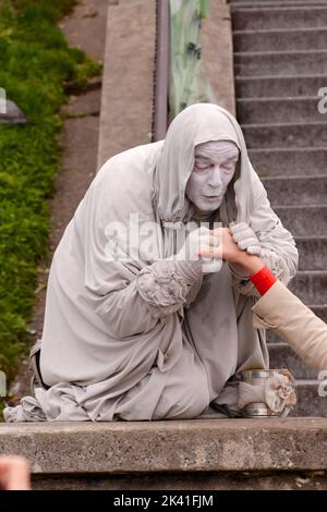 Street artist playing disguised as a white statue Stock Photo - Alamy