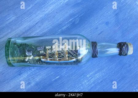Fully rigged ship in a bottle on a blue background Stock Photo - Alamy