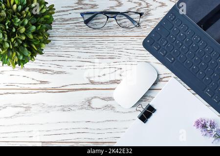 Modern laptop, houseplants on table and sticky notes on white wall ...