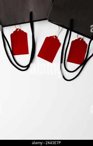 Composition of gift tags and bags with copy space on white background ...