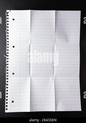 Hole punched sheet of lined paper, torn from spiral binding, folded and ...