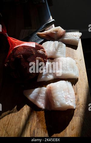 Fresh Cod fillet pinboned and a bag of fresh live clams ready for ...