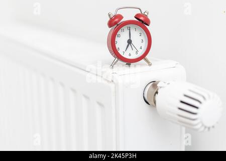 alarm clock on radiator indoors. Winter heating efficiency Stock Photo ...