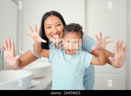 Mother teaching her young son how to wash his face in the bathroom ...