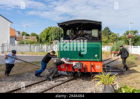 Railway workers manually operating a turntable to turn a steam ...