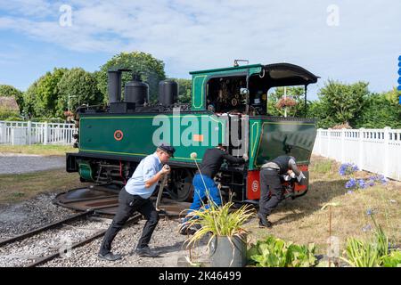 Railway workers manually operating a turntable to turn a steam ...