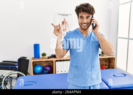 Hispanic physiotherapy man working at pain recovery clinic smiling ...