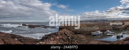 Boats and houses in Dunbar harbour during low tide. Dunbar is a town ...