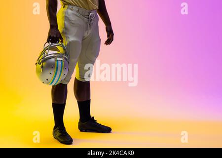 Midsection of african american male american football player with neon ...