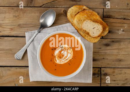 Horizontal image of bowl of tomato soup with basil leaves and napkin on ...