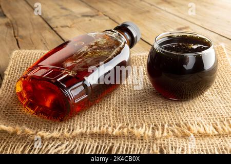Horizontal image of glass bottle and bowl of maple syrup on sackcloth ...