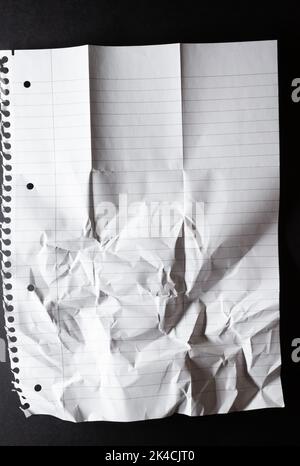 Hole punched sheet of lined paper, torn from spiral binding, folded and ...