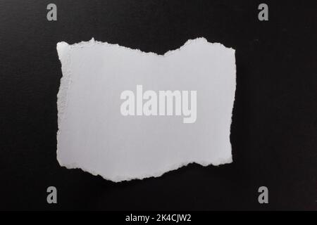 Roughly torn rectangle of white paper on black background. monochrome ...