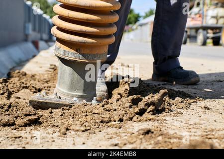 Worker using vibratory plate compactor for compaction sand during path ...