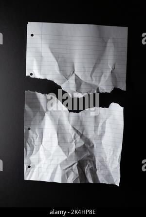 Two halves of scrunched up, hole punched sheet of lined white notebook ...