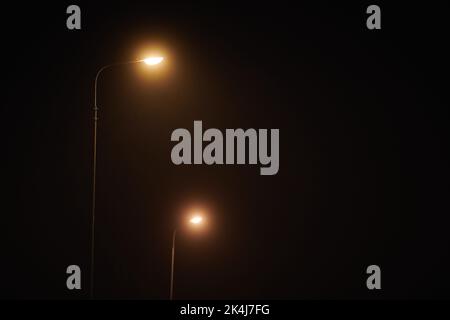 Two night lampposts shines with faint mysterious yellow light through ...