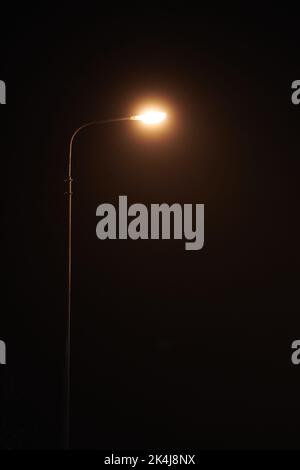 One night lamppost shines with faint mysterious yellow light through ...