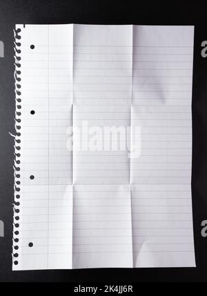 Hole punched sheet of lined paper, torn from spiral binding, folded and ...