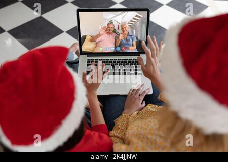 Mother and daughter making laptop christmas video call with smiling ...