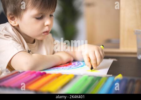 Enthusiastic male kid drawing multicolor rainbow paper sheet closeup ...